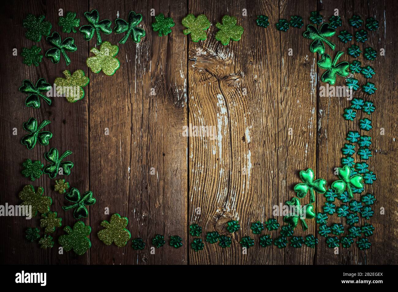 St Patricks Day frame of glittery shamrocks over an old rustic wood ...
