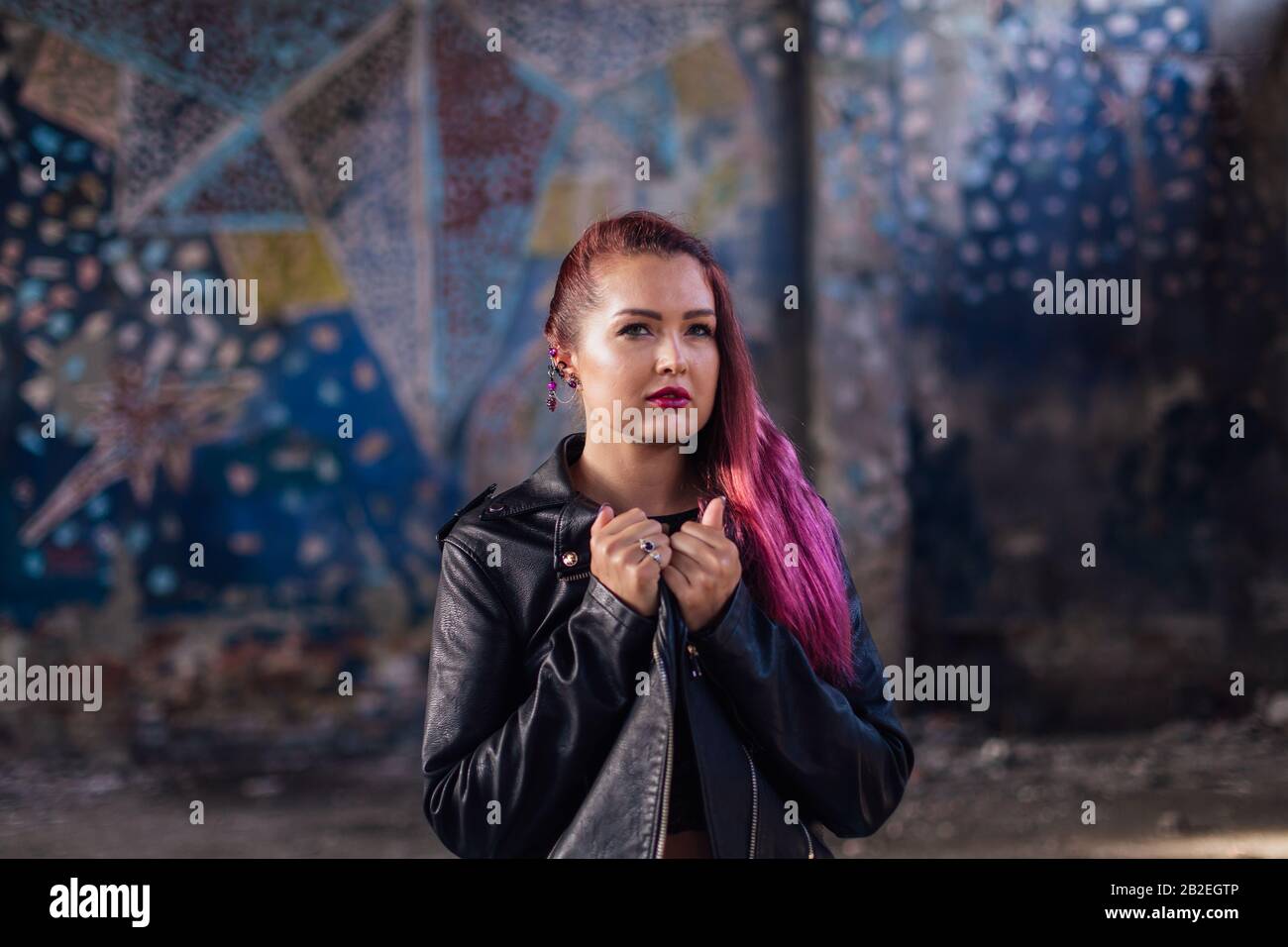 Portrait of a young girl with pink hair standing inside of collapsed ...