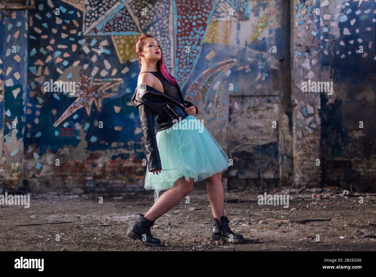 Portrait of a young girl with pink hair standing inside of collapsed ...