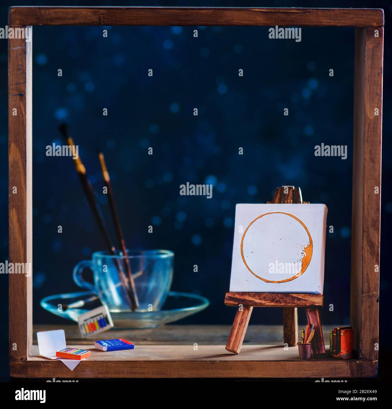 Miniature easel with coffee cup stain with artist tools in a wooden ...