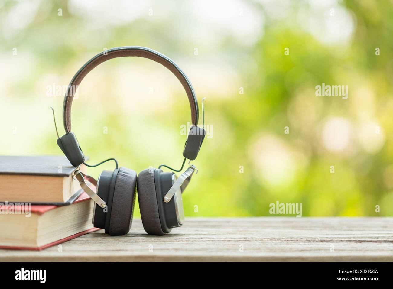 Close up book and black headphone on wooden table with abstract green ...