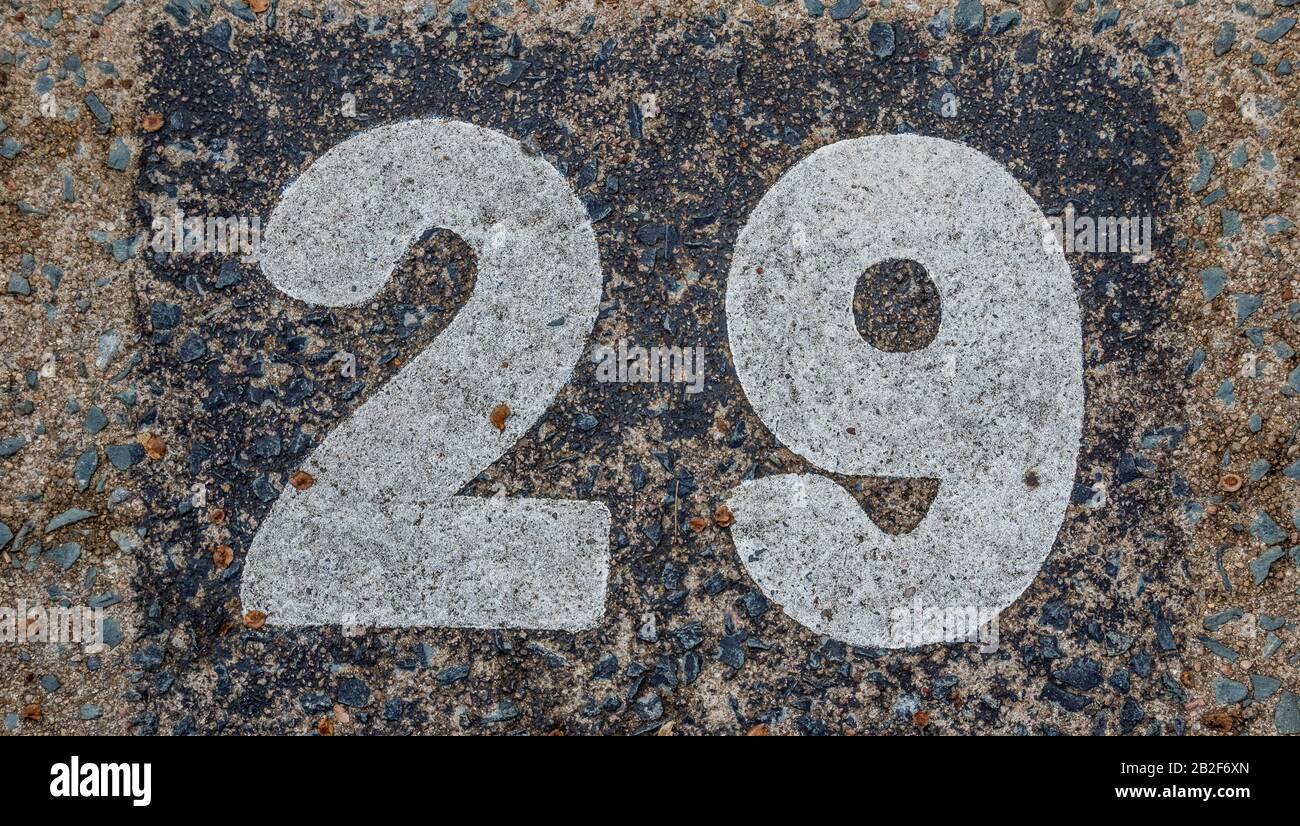 Weathered and faded number twenty nine painted on a rough concrete ...