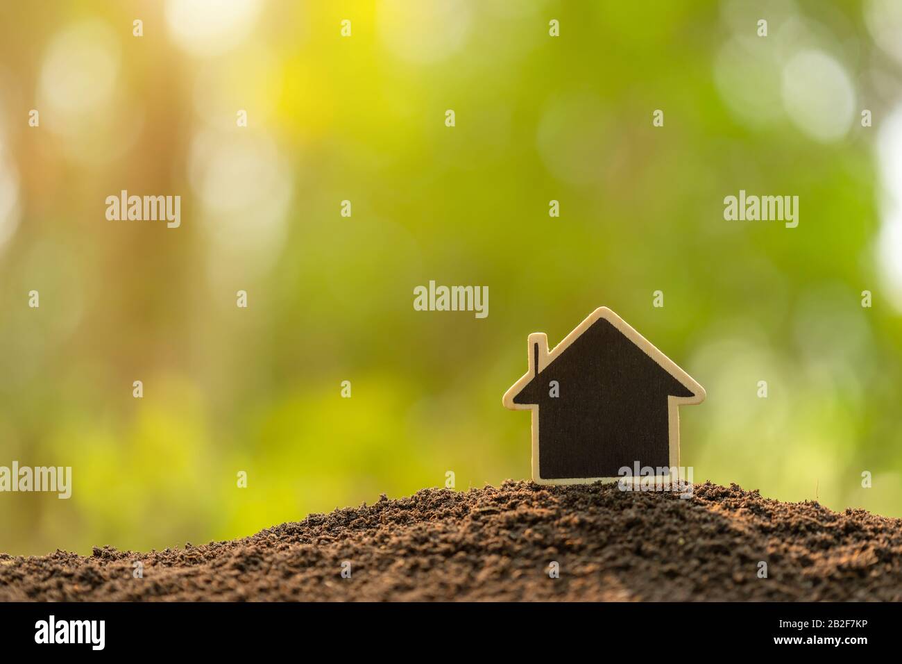 Close up wooden house growing in soil on green nature blur background ...