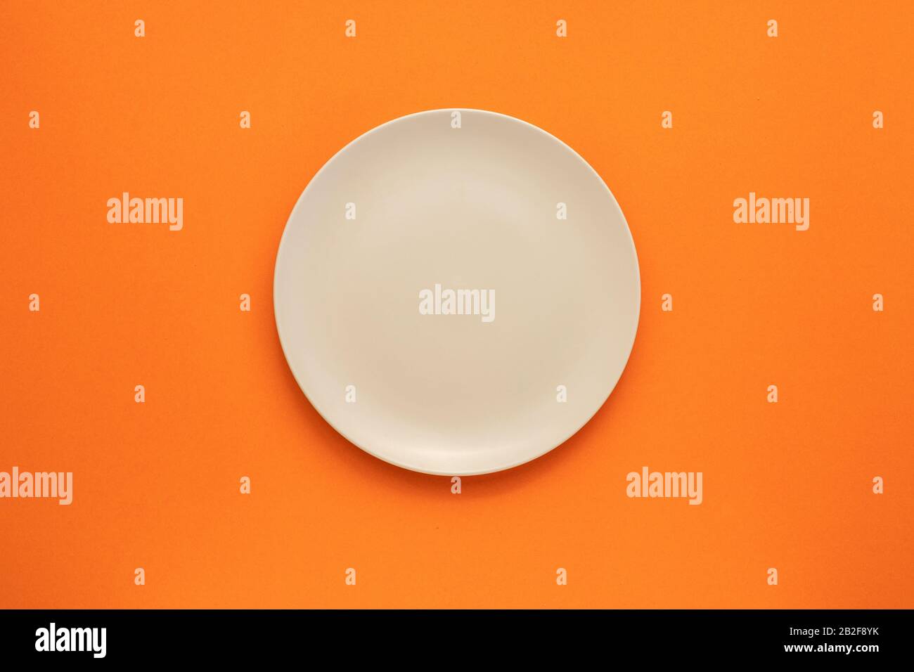 Top view empty white ceramic dish on the middle of orange background ...