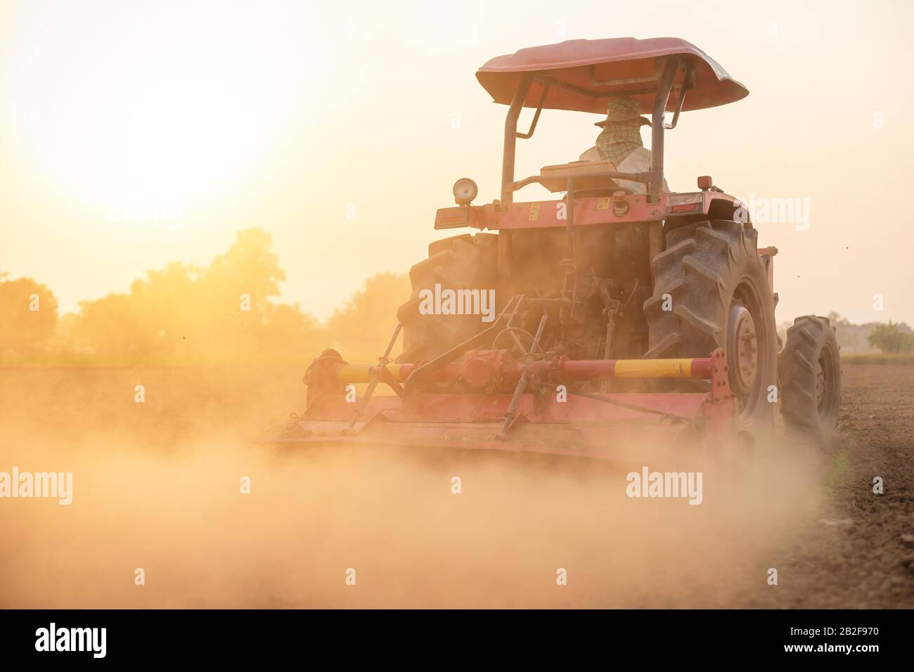 Thai farmer on big tractor in the land to prepare the soil for rice or ...