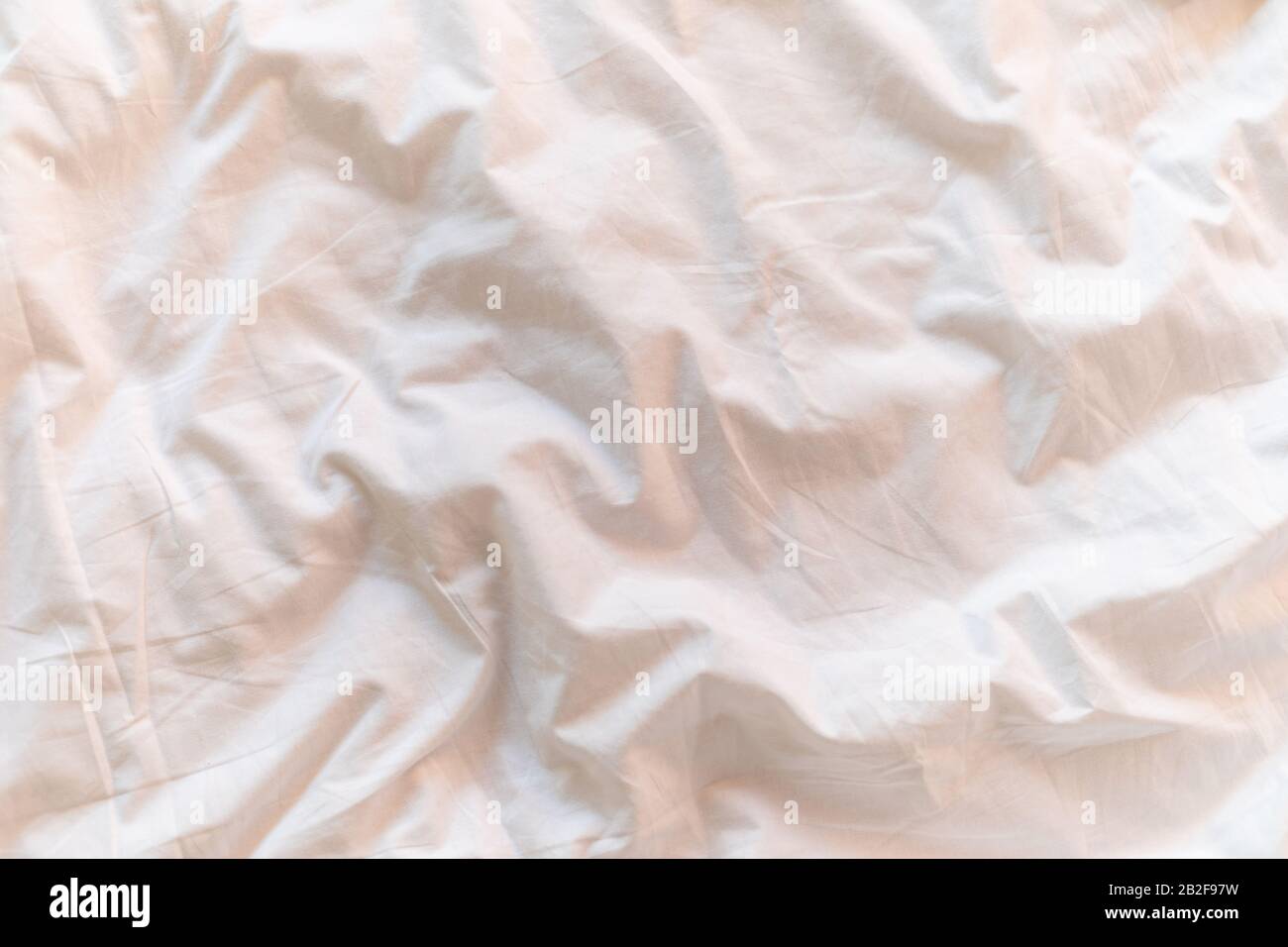 Close up white bedding sheets and pillow in hotel room at morning time ...