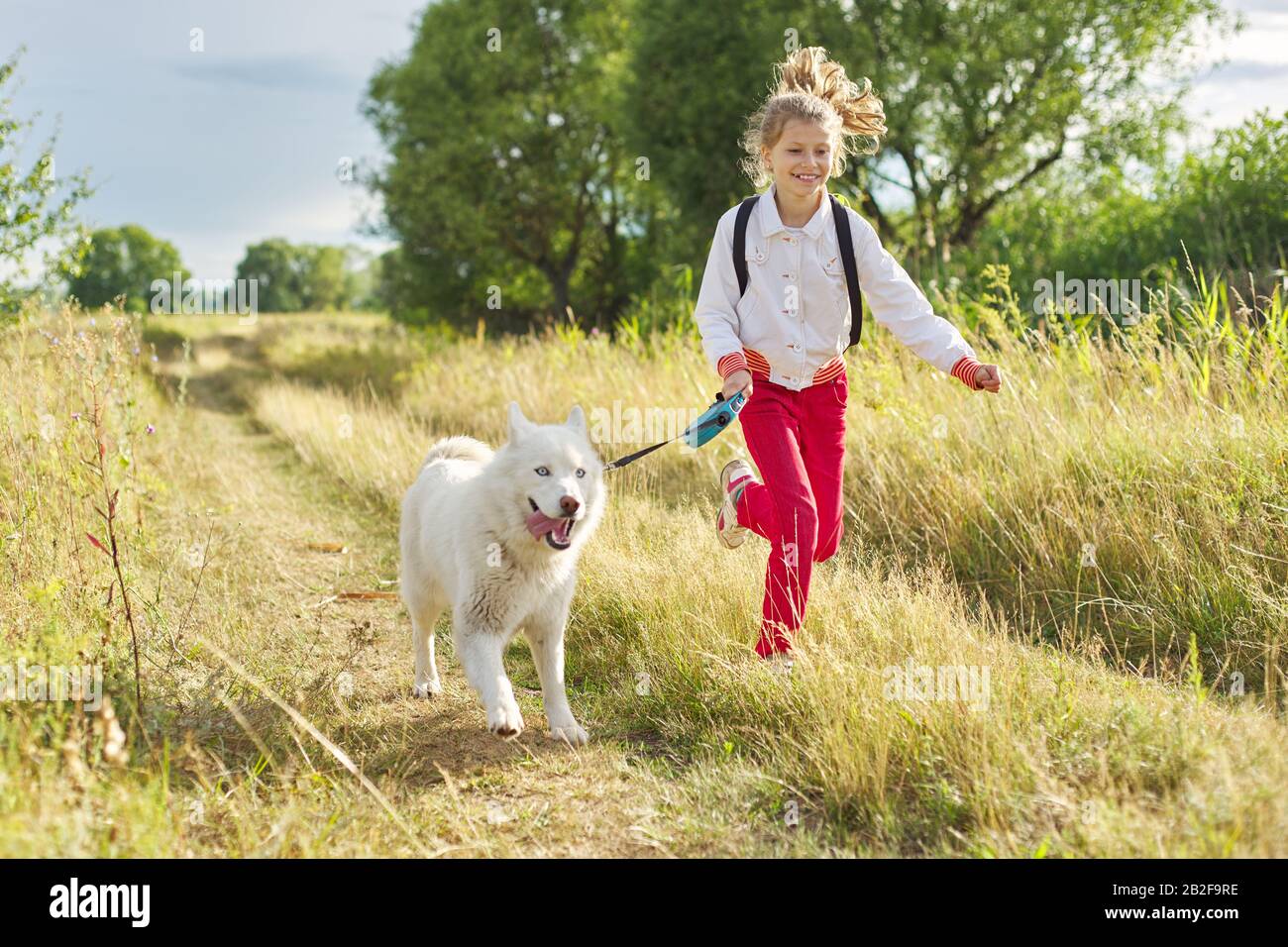 Little girl child running with white dog in meadow Stock Photo - Alamy