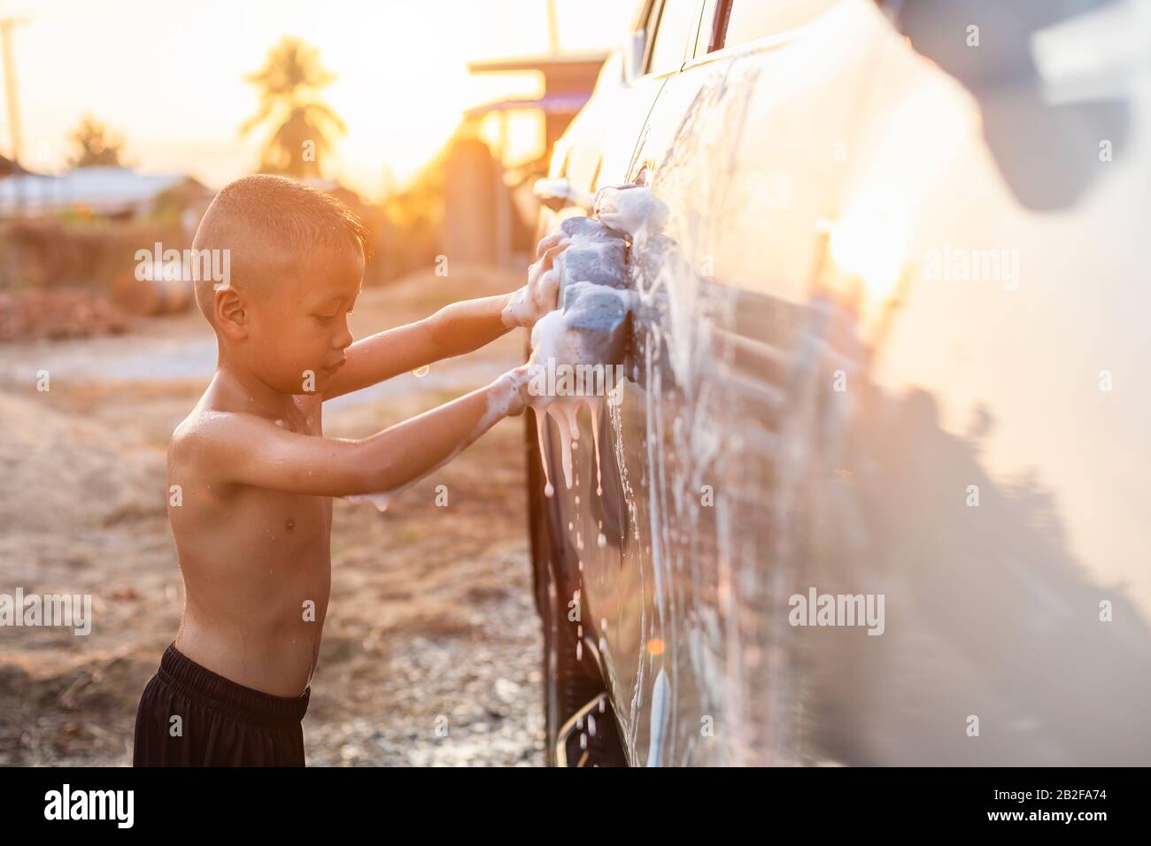 Happy asian little boy playing white soap and using blue sponge to ...