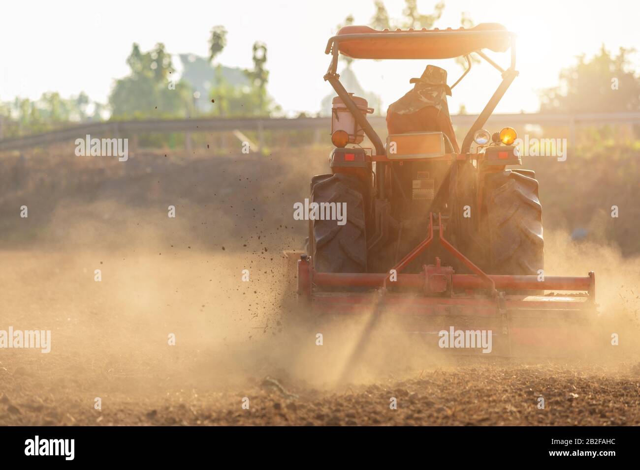 Thai farmer on big tractor in the land to prepare the soil for rice or ...