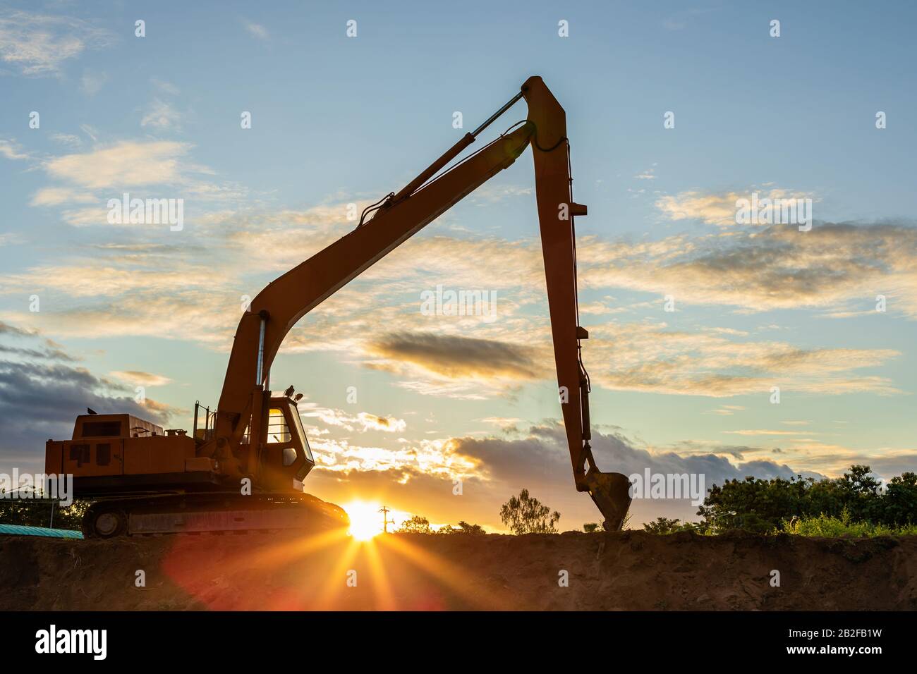 Silhouette of big tracked excavator digging the soil on site. Shoot in ...