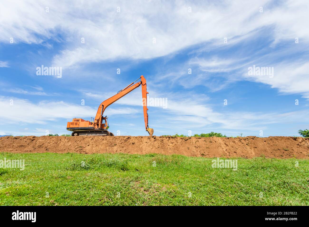 Big orange tracked excavator operate and digging the soil on site ...