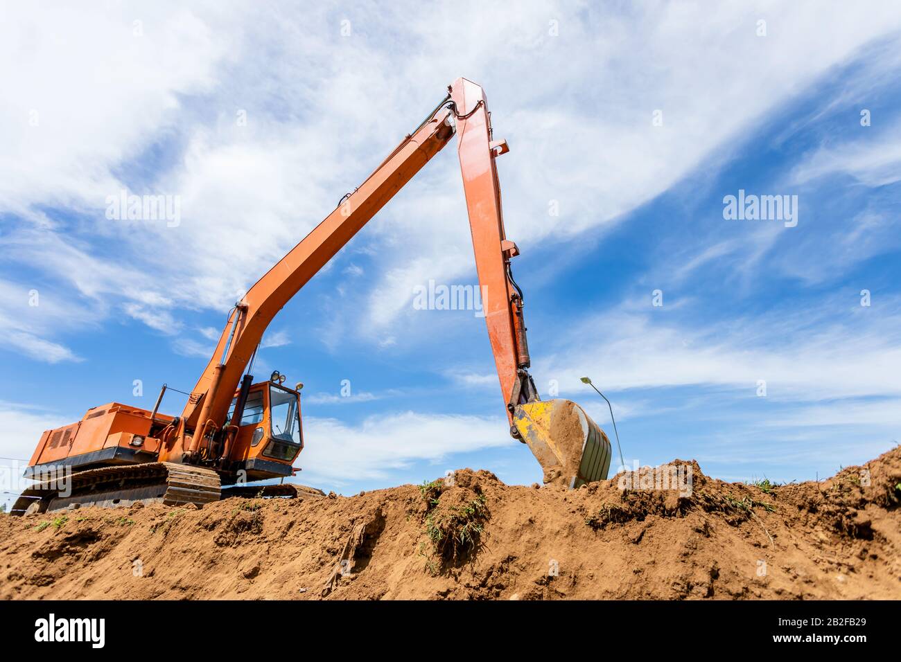 Big orange tracked excavator operate and digging the soil on site ...