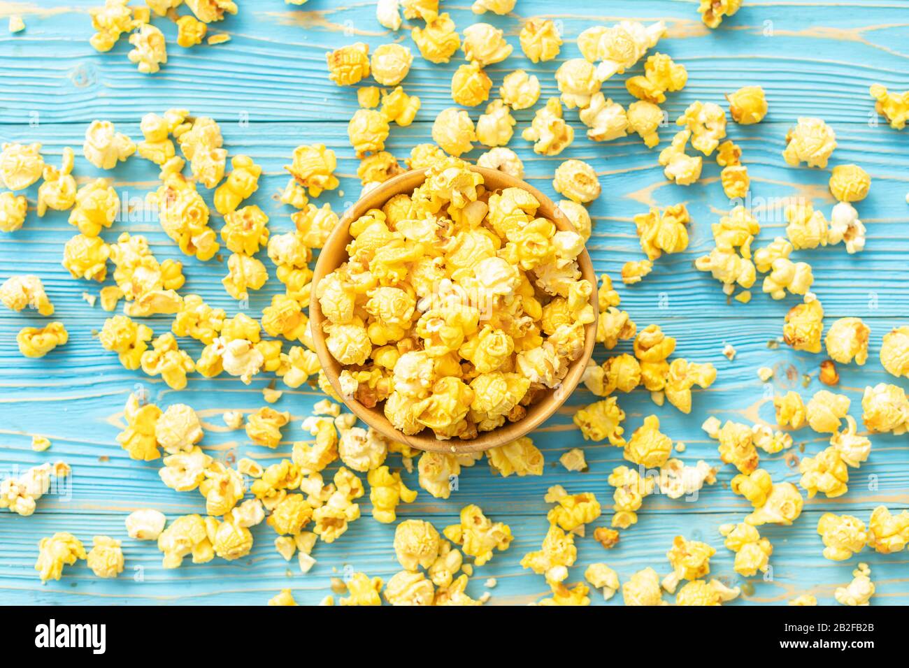 Top view yellow popcorn on blue wooden plank background. Food or snack ...