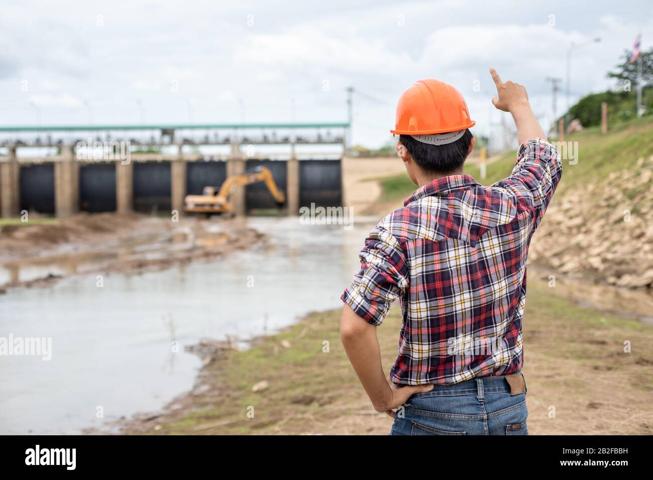 Asian young engineer working on site at the dam and control while ...