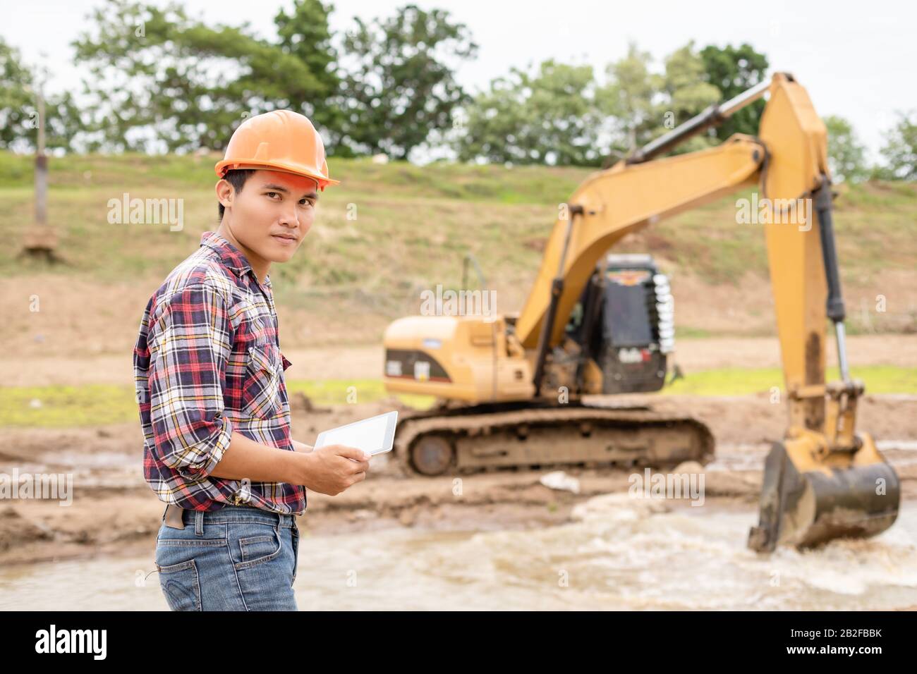 Asian young engineer working on site at the dam and control while ...