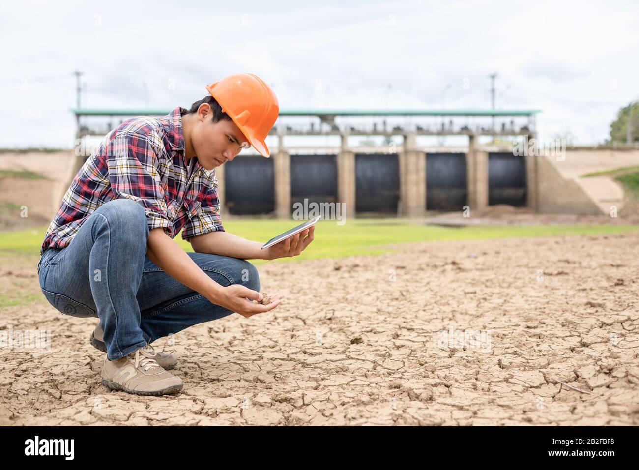 Asian young engineer working on site at the dam and checking the soil ...