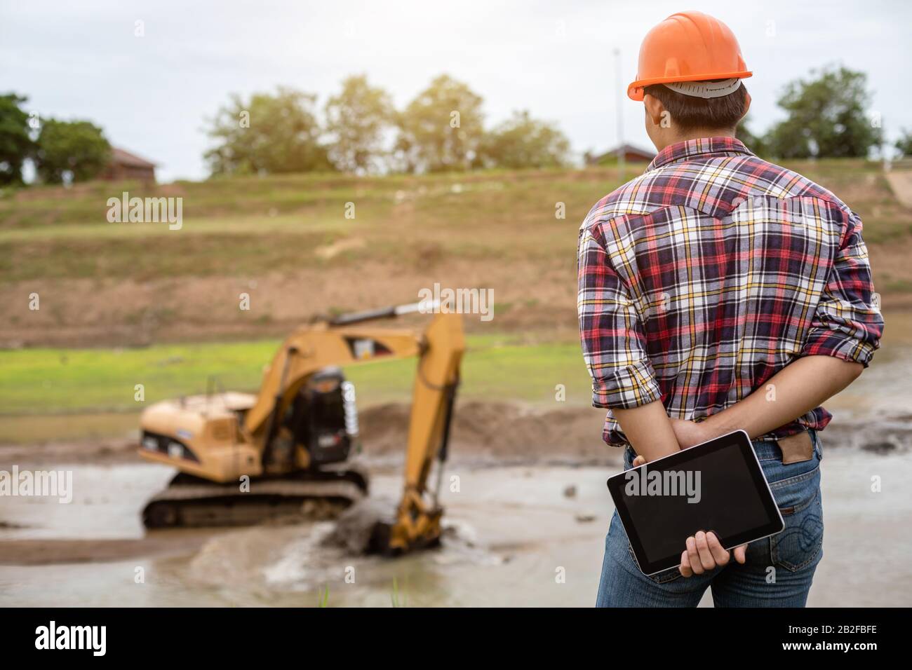 Asian young engineer working on site at the dam and control while ...