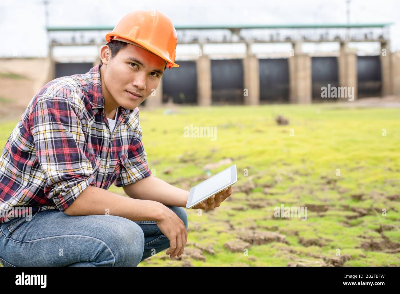 Asian young engineer working on site at the dam and checking the soil ...