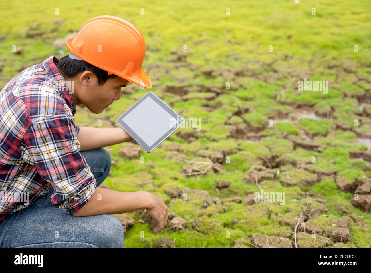 Asian young engineer working on site at the dam and checking the soil ...