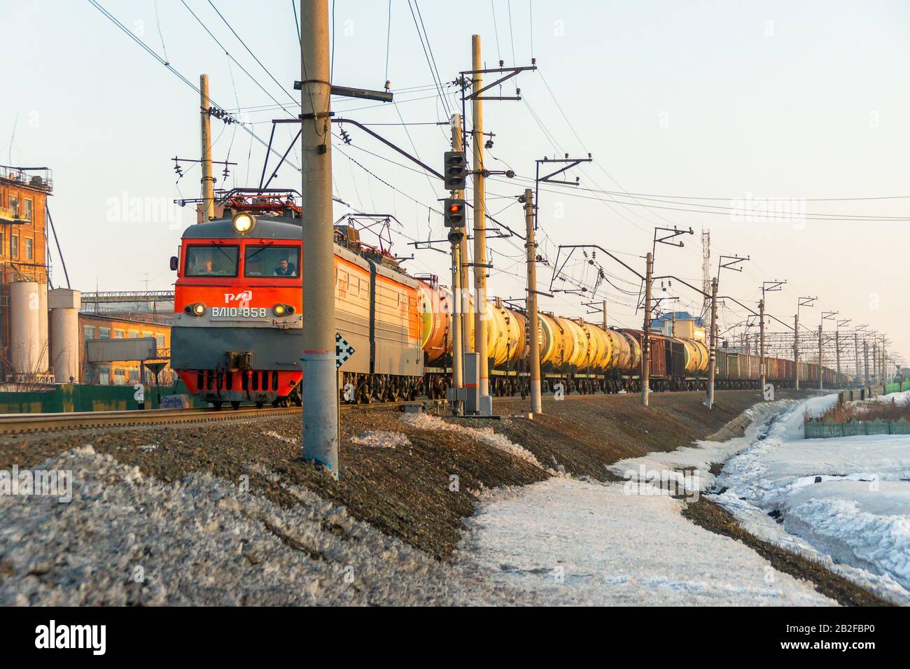 red locomotive of Russian Railways carries a freight train with tanks ...