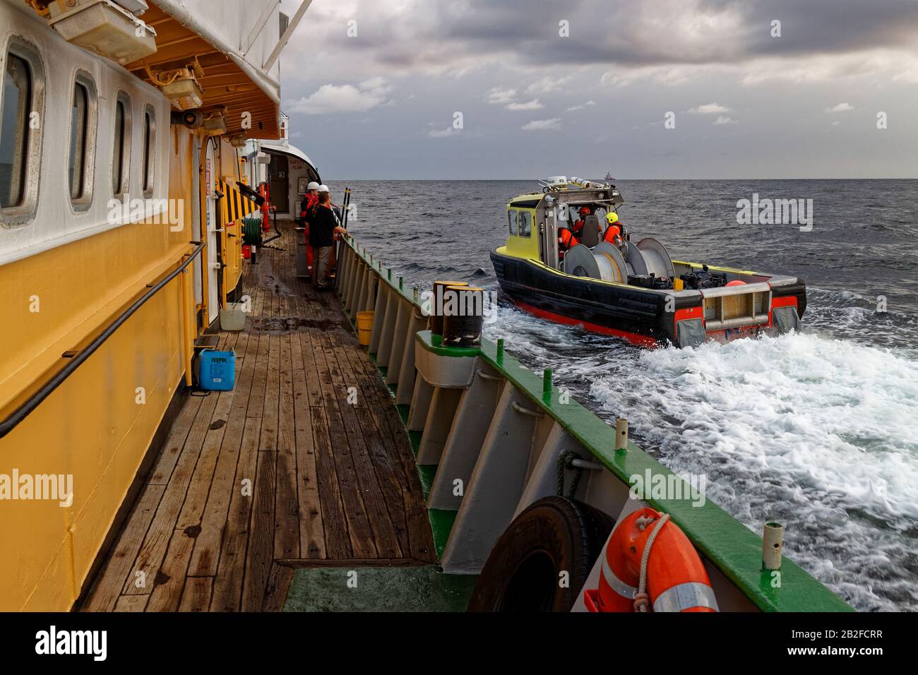 A Seismic Workboat approaches the side of an Escort Vessel in the ...