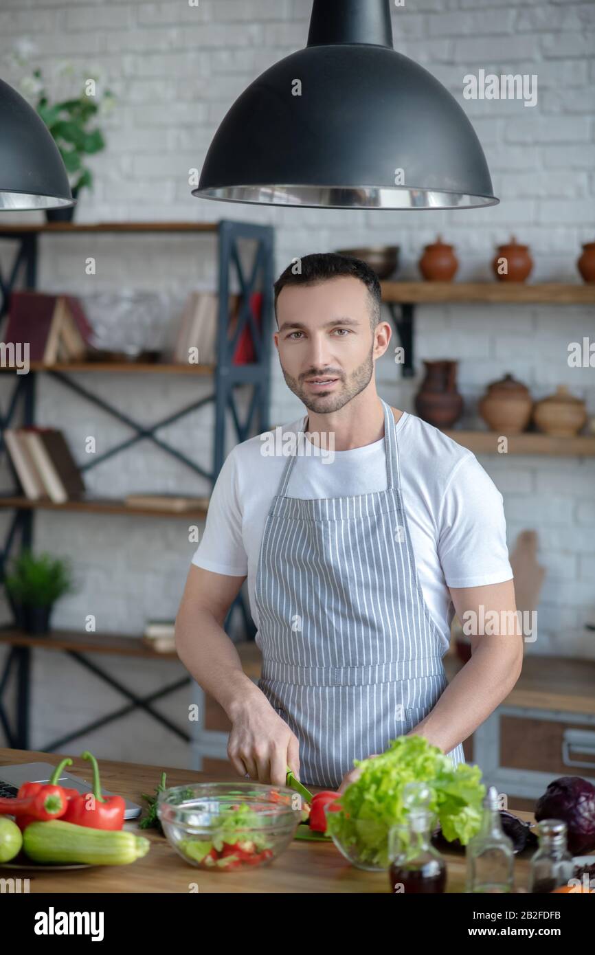 Young guy in an apron preparing vegetable food Stock Photo - Alamy