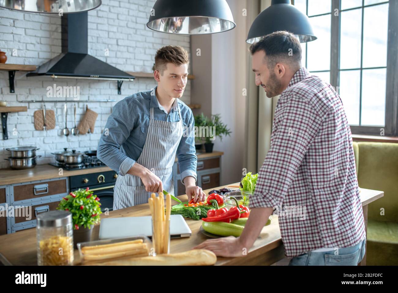 Two men standing opposite each other near the kitchen table Stock Photo ...
