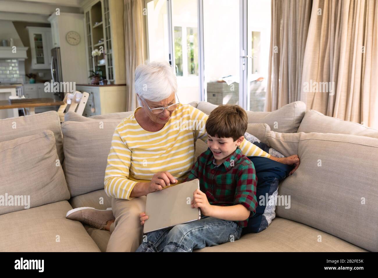 Front view of a Caucasian grandmother at home sitting on a sofa in the ...