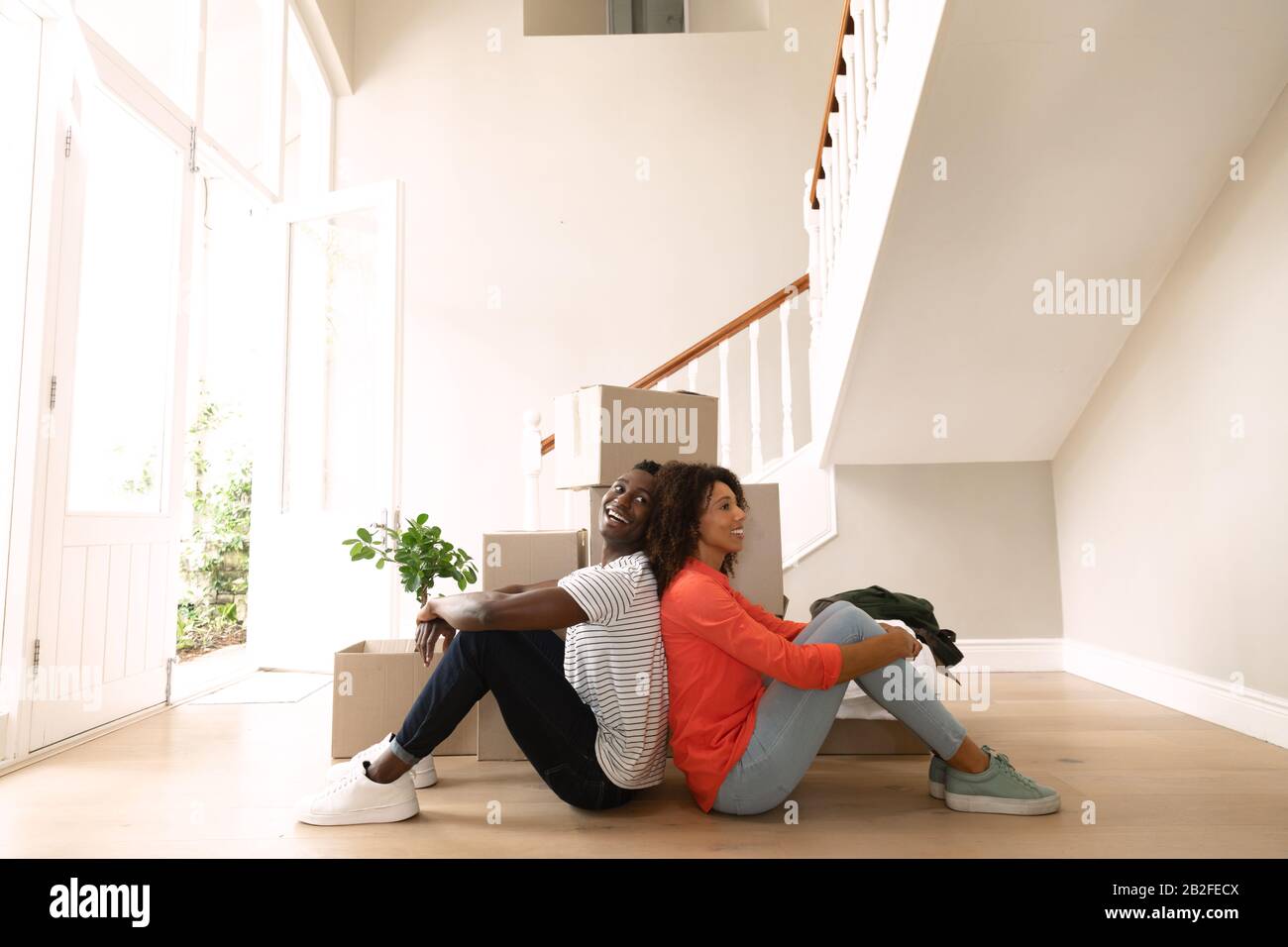 Side view of an African American couple at home, moving in, sitting on ...