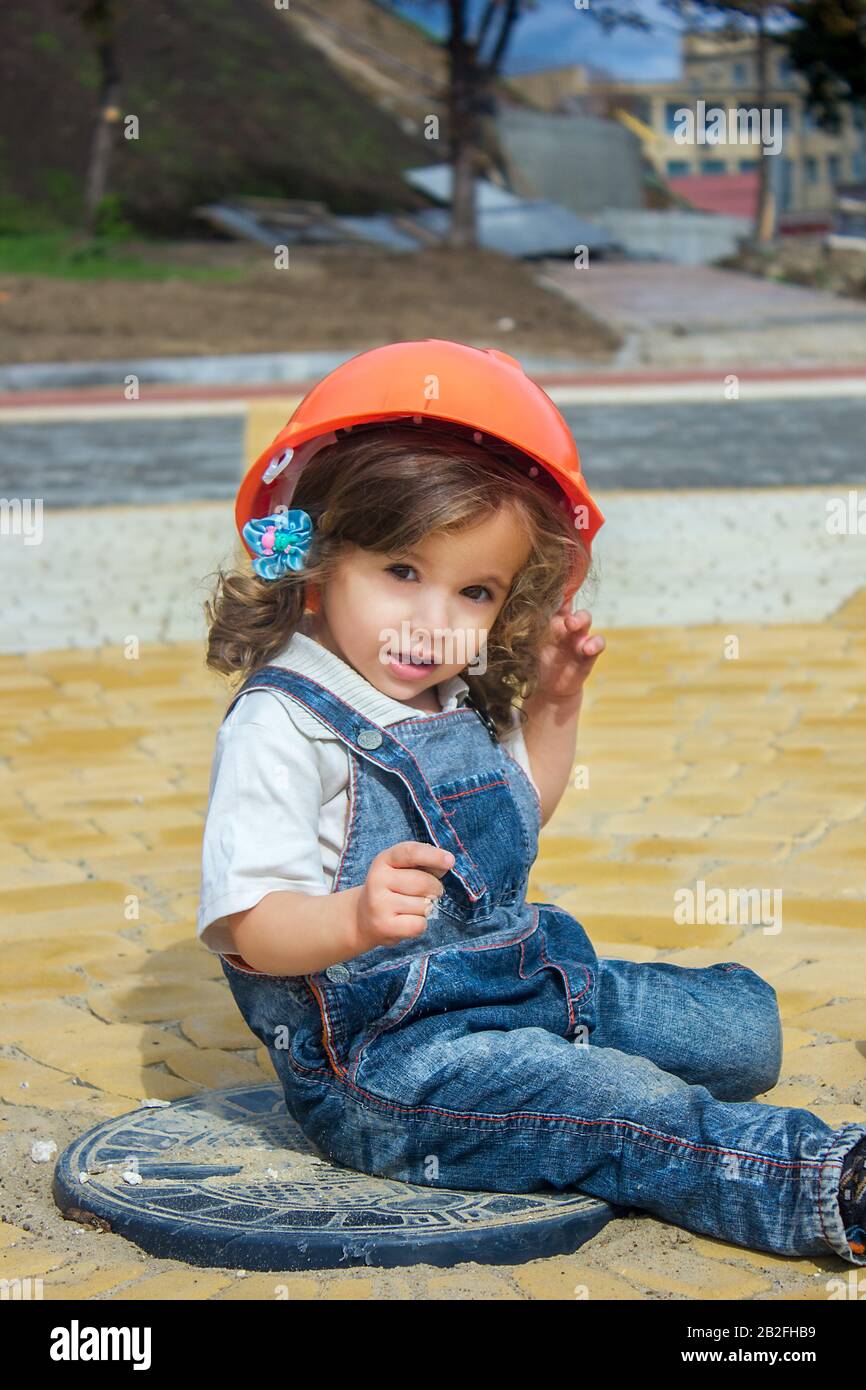 Little baby girl builder with the construction helmet and poster in ...