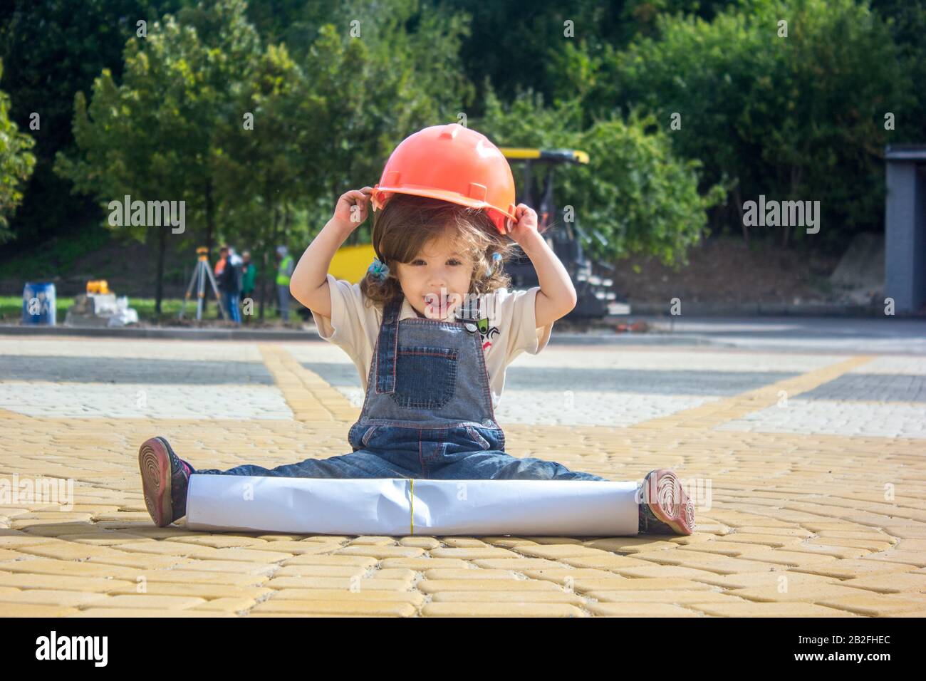 Little baby girl builder with the construction helmet and poster in ...