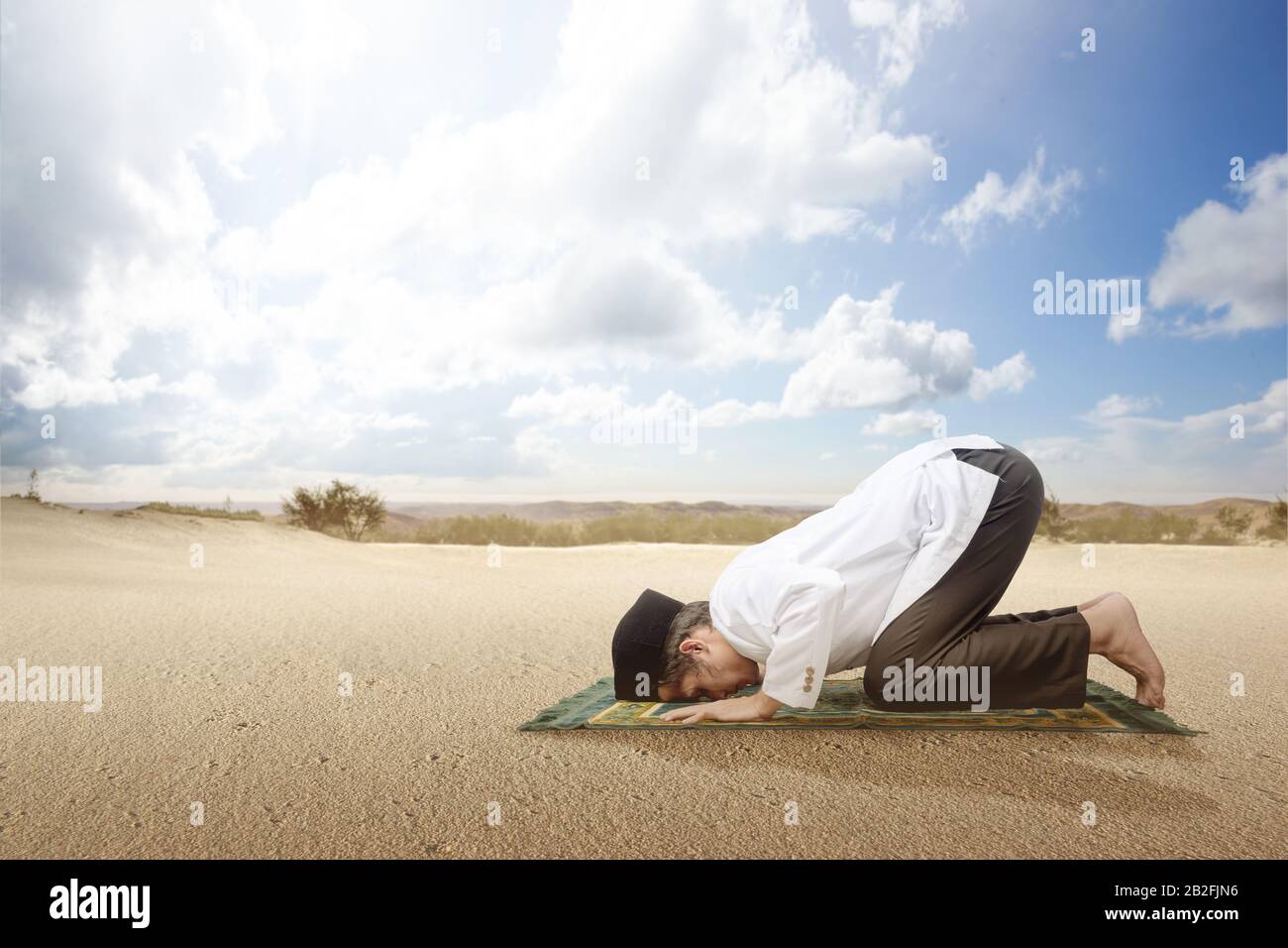 Asian Muslim man with a prayer rug in a praying position (salat) on the ...