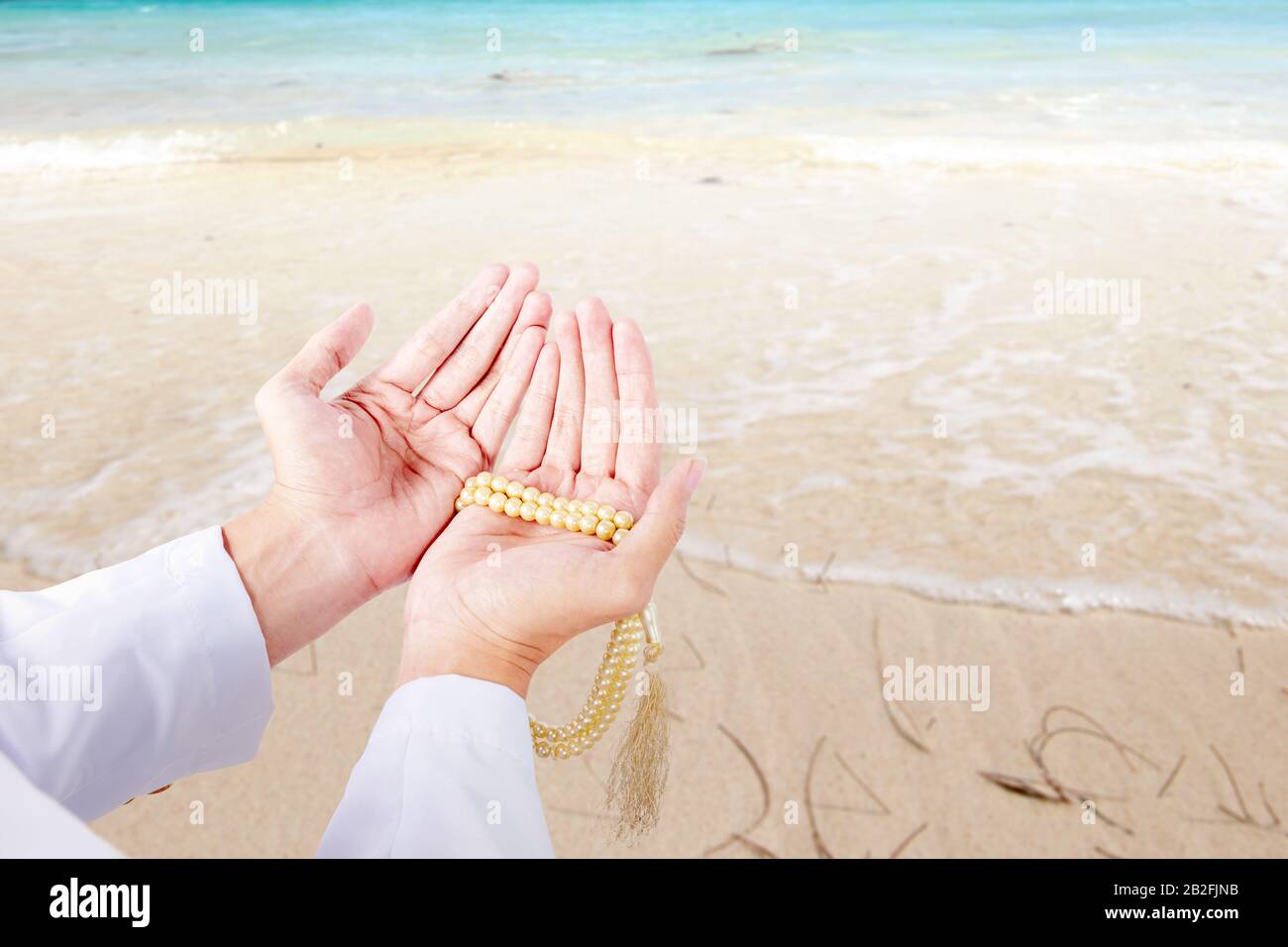 Muslim man praying with prayer beads on his hands on the beach Stock ...