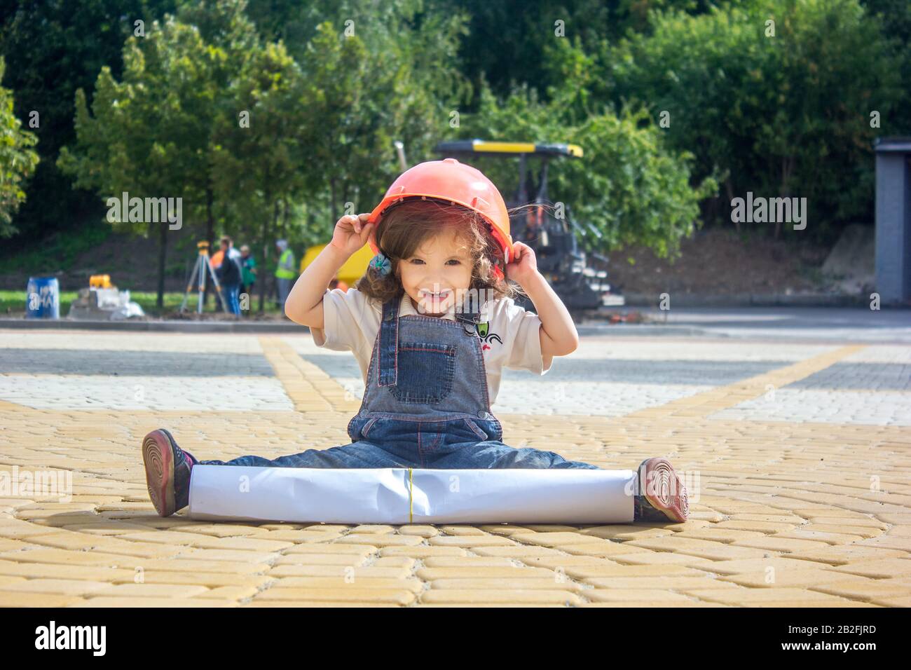Little baby girl builder with the construction helmet and poster in ...