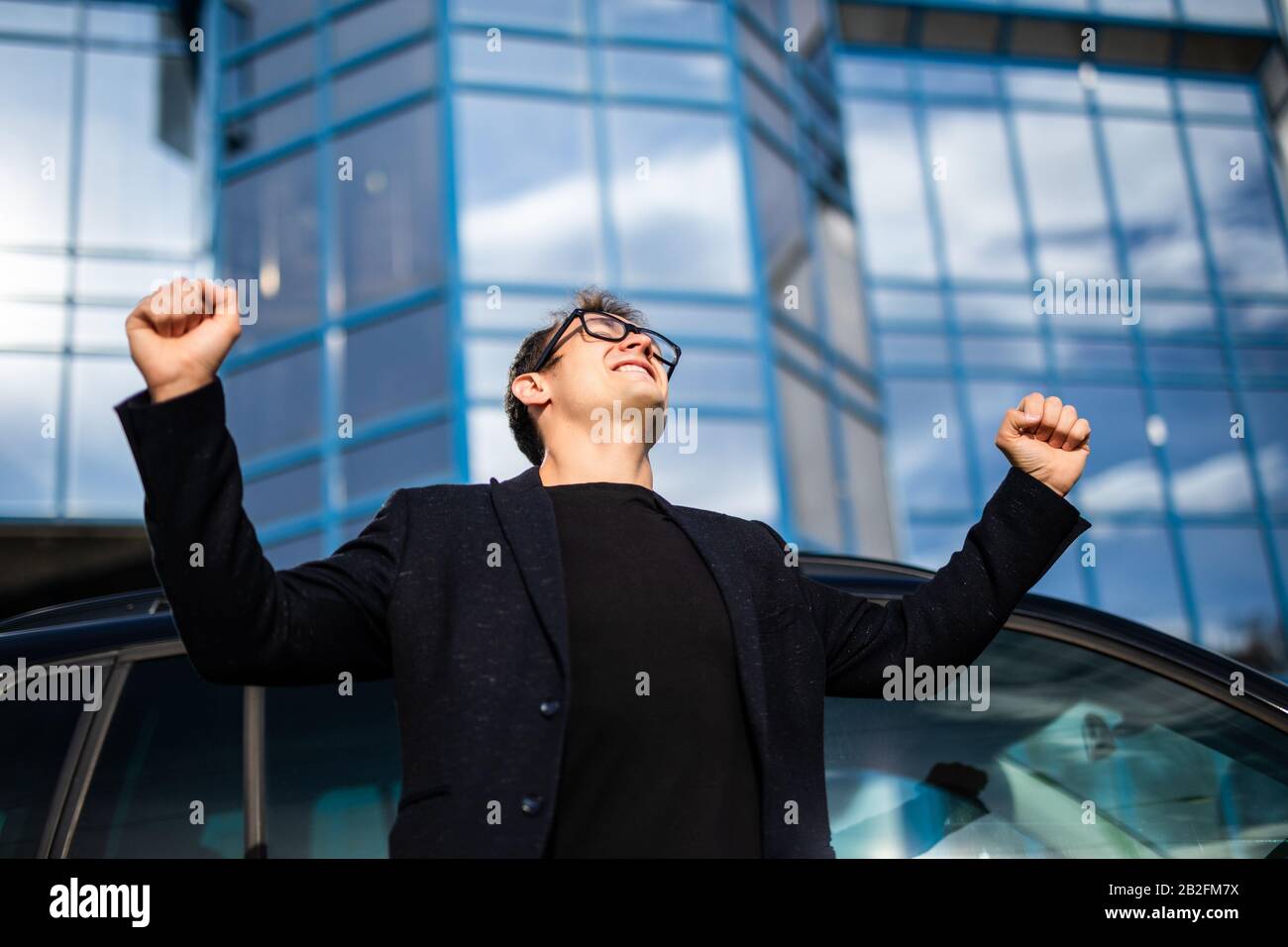 A young successful man, male executive businessman arms raised ...