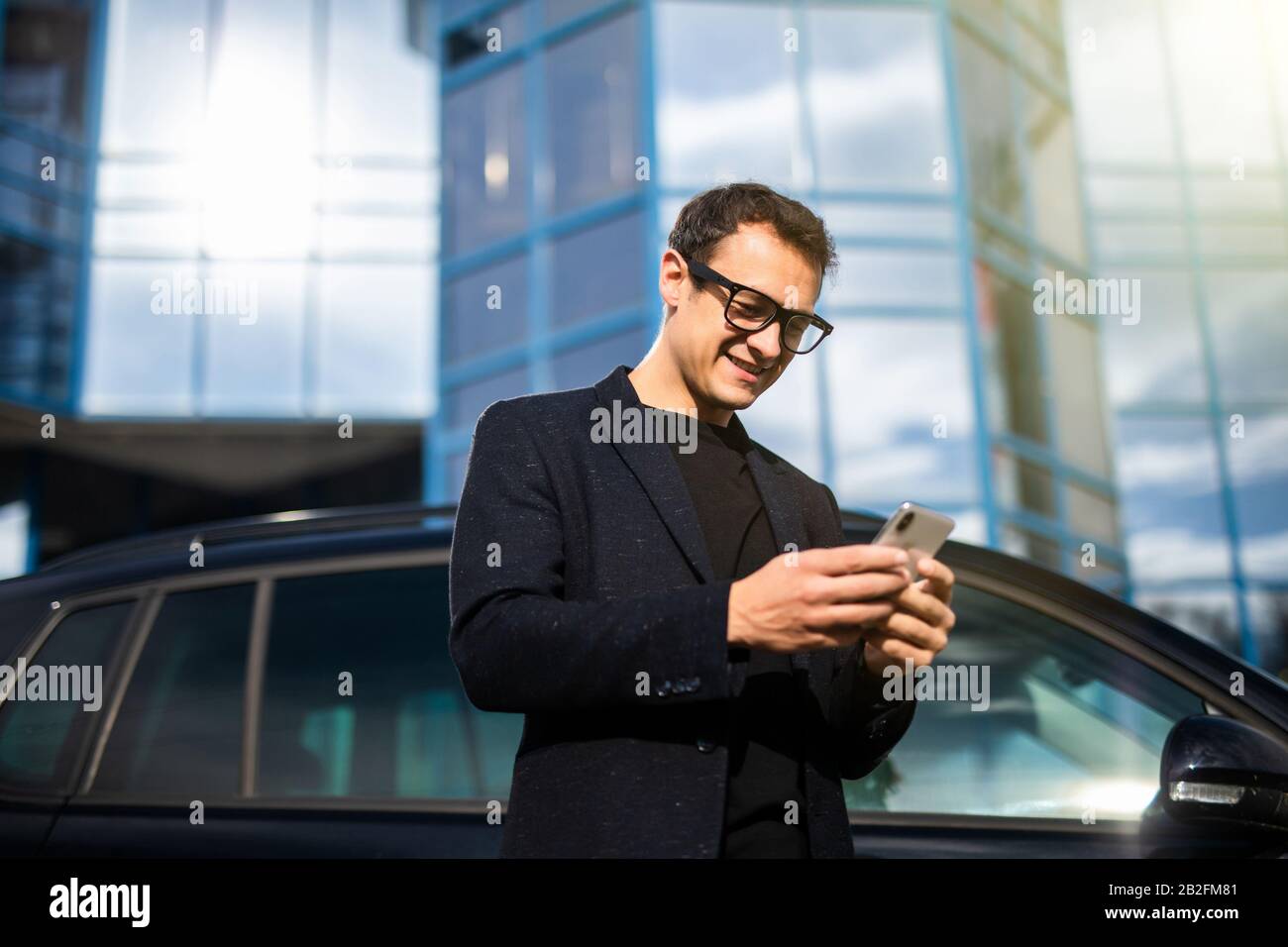 Half length of happy businessman reading text message on cell phone ...