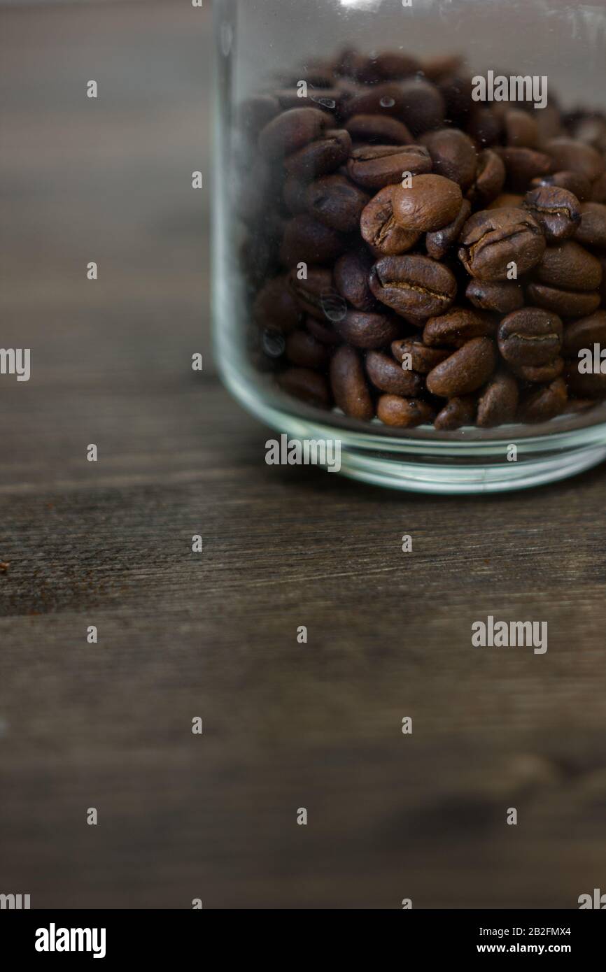 Transparent glass coffee jar filled with beans of coffee over the dark ...