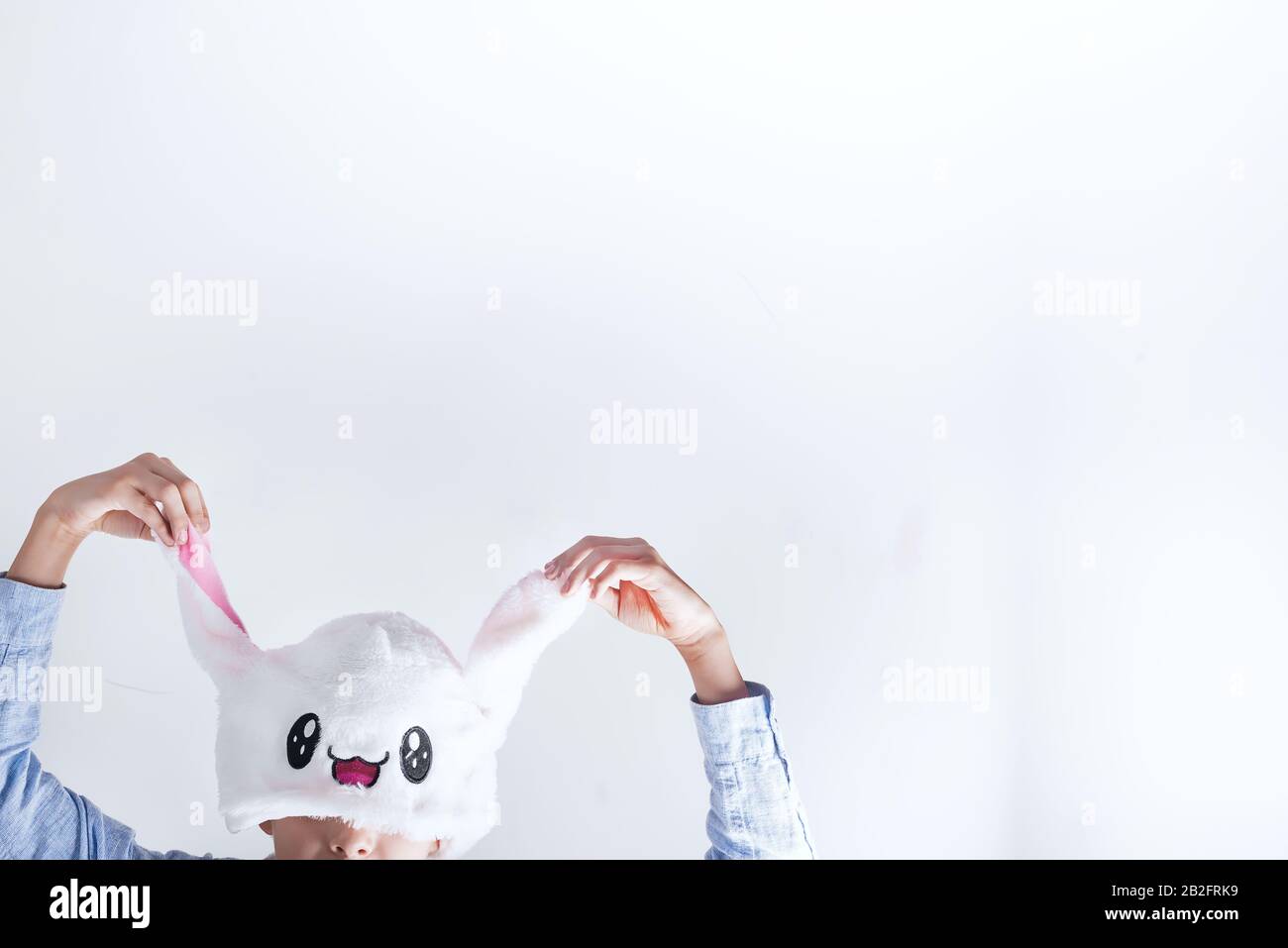 A boy holds hands ears hat Kawaii Rabbit on a light background, Easter ...