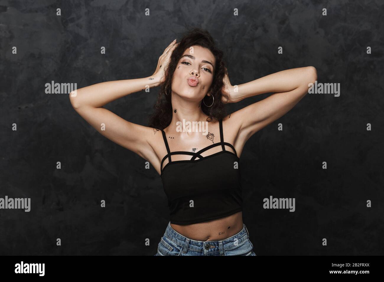 Image of young joyful woman with tattoo making kiss lips and grabbing ...