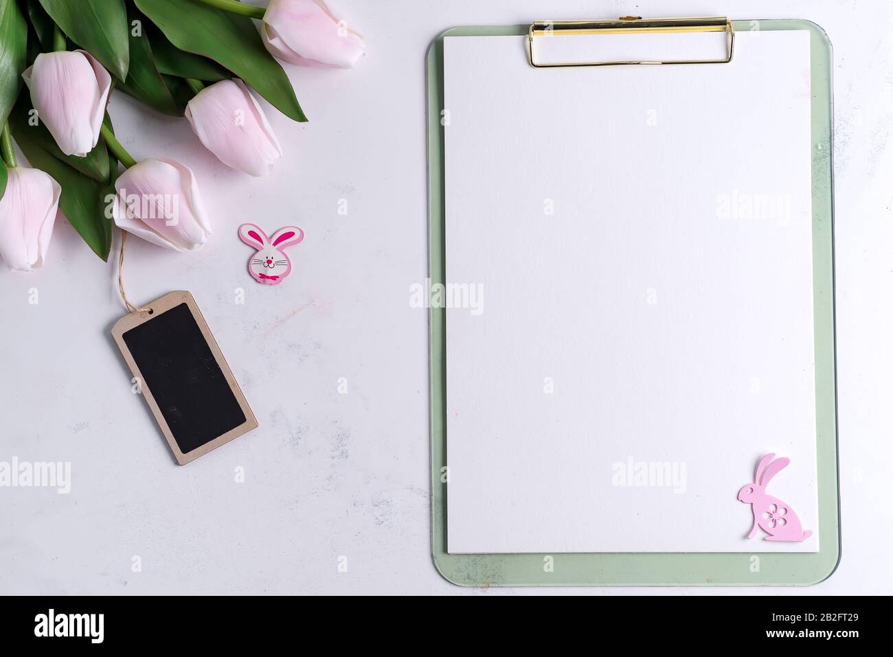 Clipboard with spring tulips with easter bunny on a marble background ...