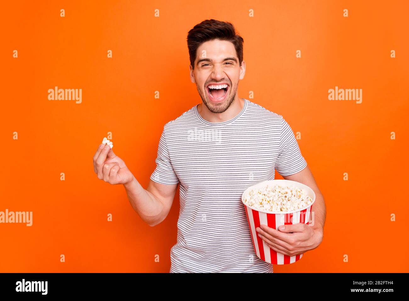 Photo of attractive crazy funky guy watch television humor show eat popcorn laughing out loud ...