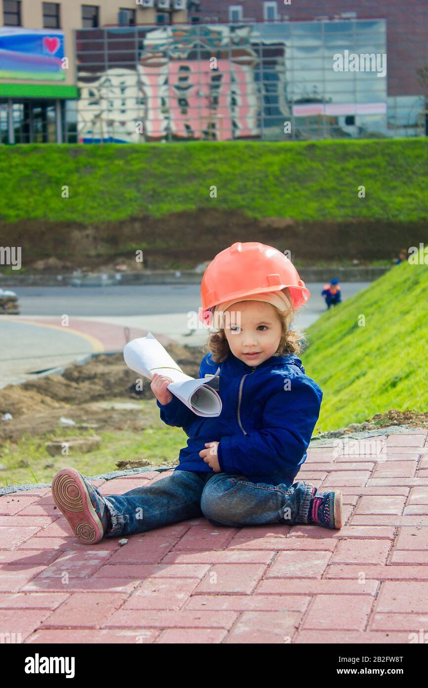Little baby girl builder with the construction helmet and poster in ...