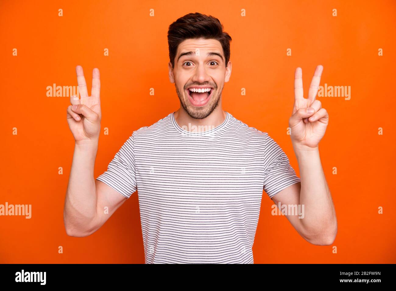 Photo of cool funny guy open mouth raise hands showing v-sign symbols ...