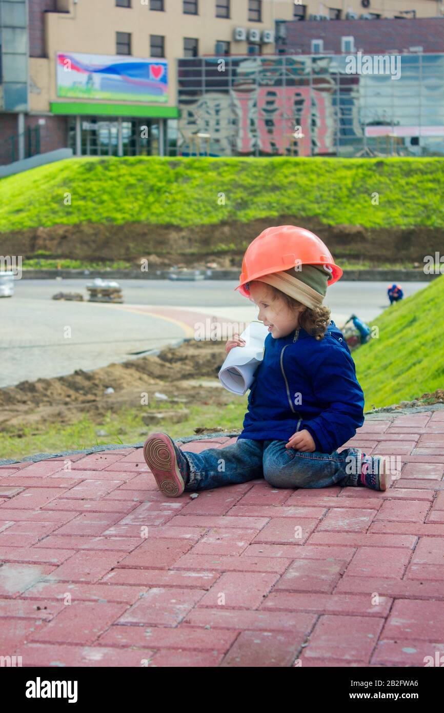 Little baby girl builder with the construction helmet and poster in ...