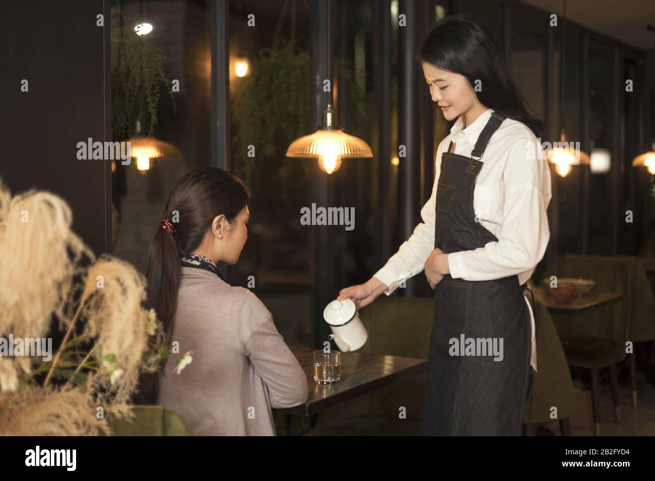 Waitress pouring tea into glass Stock Photo - Alamy