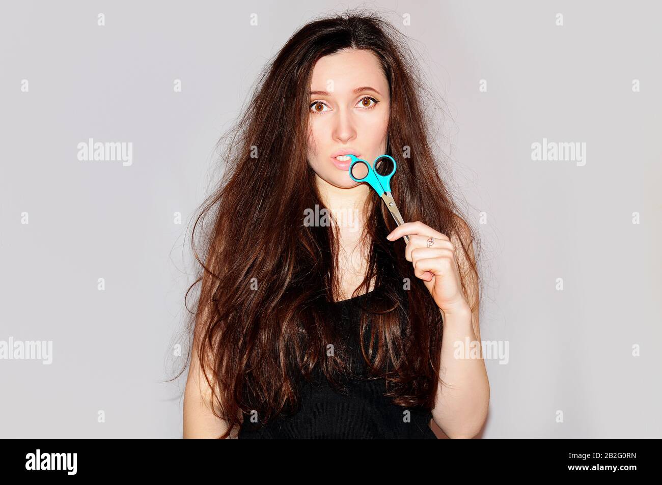 Health and beauty. Beautiful young woman with scissors in hand looking ...