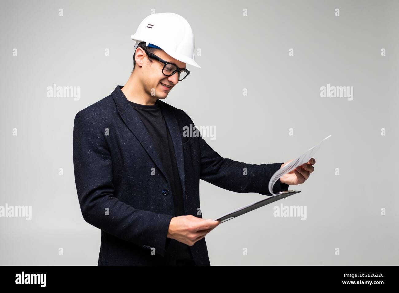 Happy male architect writing notes on clip board against white ...