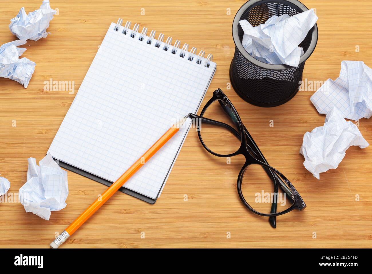 White note pad on a wooden table. Around the notepads lies lot crumpled ...