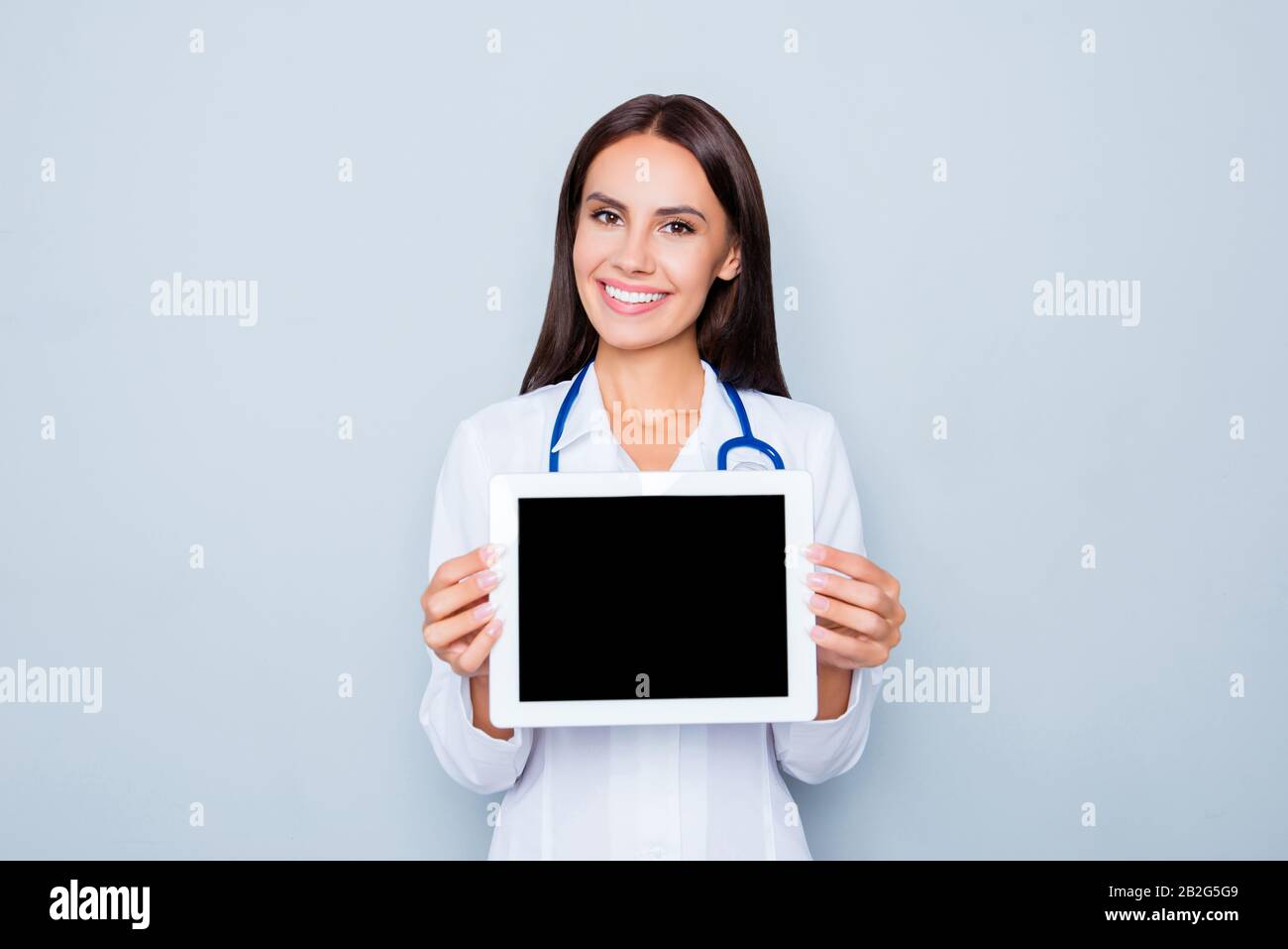 Pretty smiling doctor showing black screen of tablet Stock Photo - Alamy