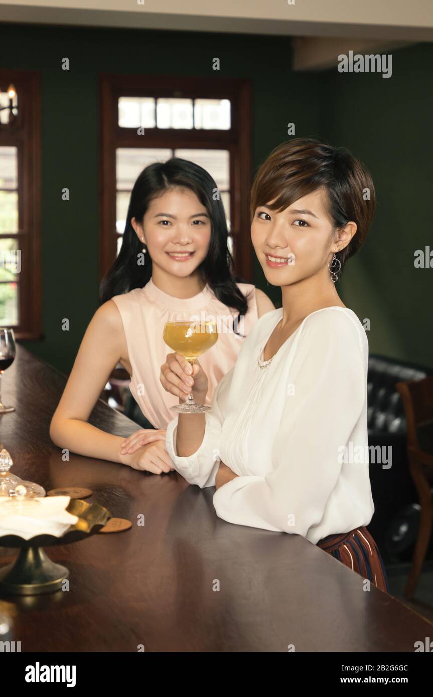 Two young women with cocktail at bar Stock Photo - Alamy